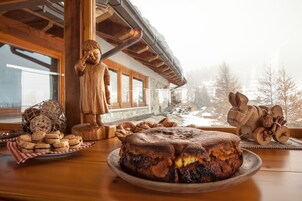 Uma mesa de madeira com um bolo, biscoitos e uma escultura de madeira.