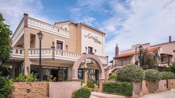 Um hotel com estrutura em dois andares, varanda e área de jardim ajardinada.