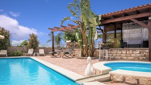 Piscina com espreguiçadeiras e área de estar coberta.