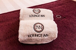 Uma toalha branca dobrada com a inscrição bordada 'Lounge Inn'.