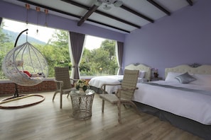 Um quarto com uma cama grande, duas cadeiras de vime, uma cadeira suspensa e uma mesa pequena com flores.