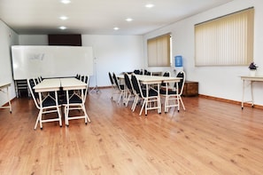 Uma sala de conferências com quadro branco, mesas, cadeiras e um bebedouro.
