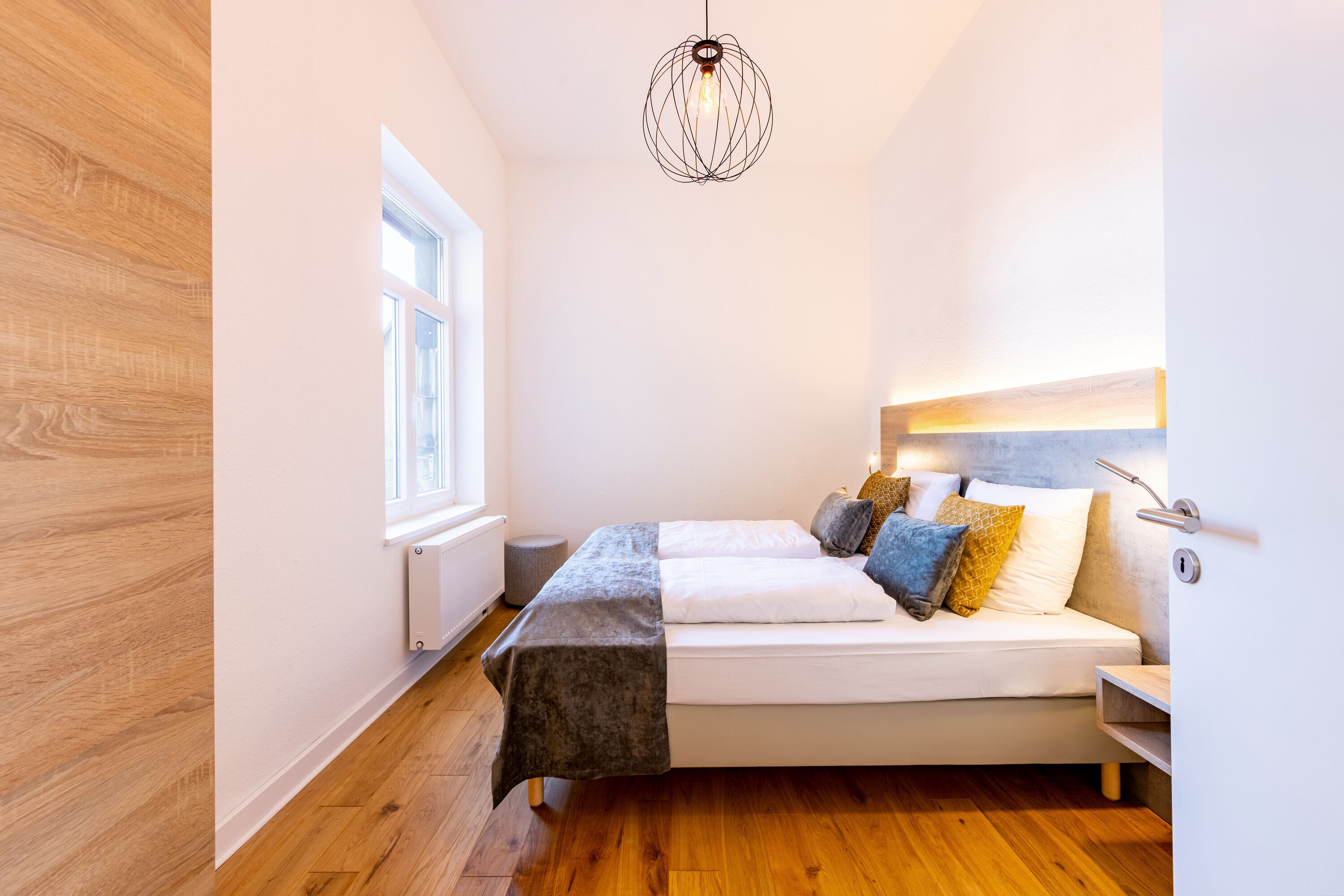 Quarto moderno com cama, mesa de cabeceira, luminária e um pendente de design.