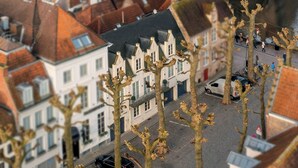 Uma maquete de uma cidade europeia com ruas estreitas, edifícios tradicionais e árvores sem folhas.