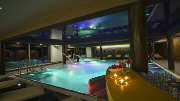 Uma área moderna de piscina interna com bar e assentos de lounge.
