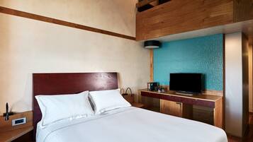 Quarto de hotel com uma cama grande, uma escrivaninha de madeira e uma televisão de tela plana, além de uma parede verde-água com textura.