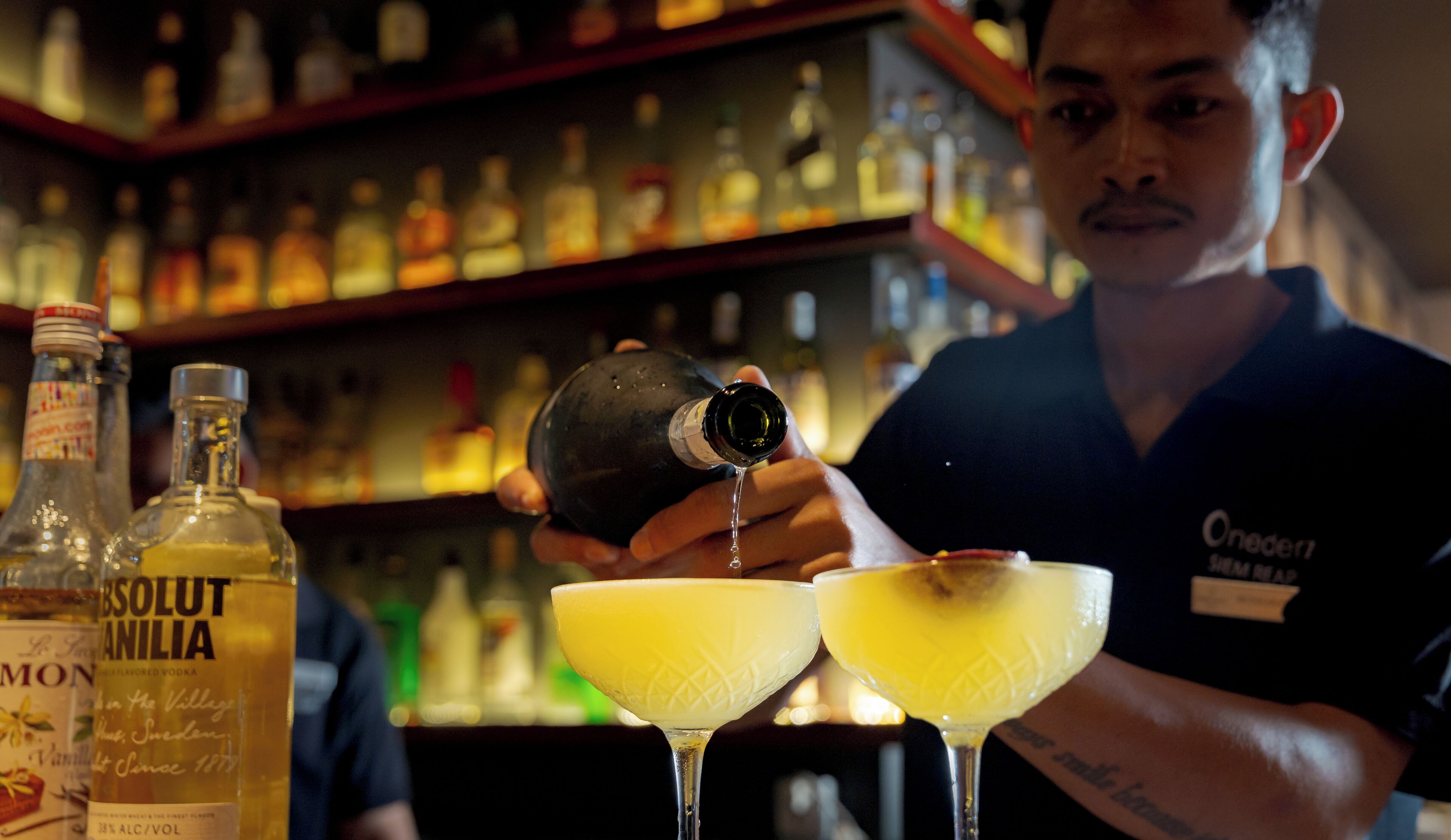 Um bartender a servir uma bebida num copo de martini.
