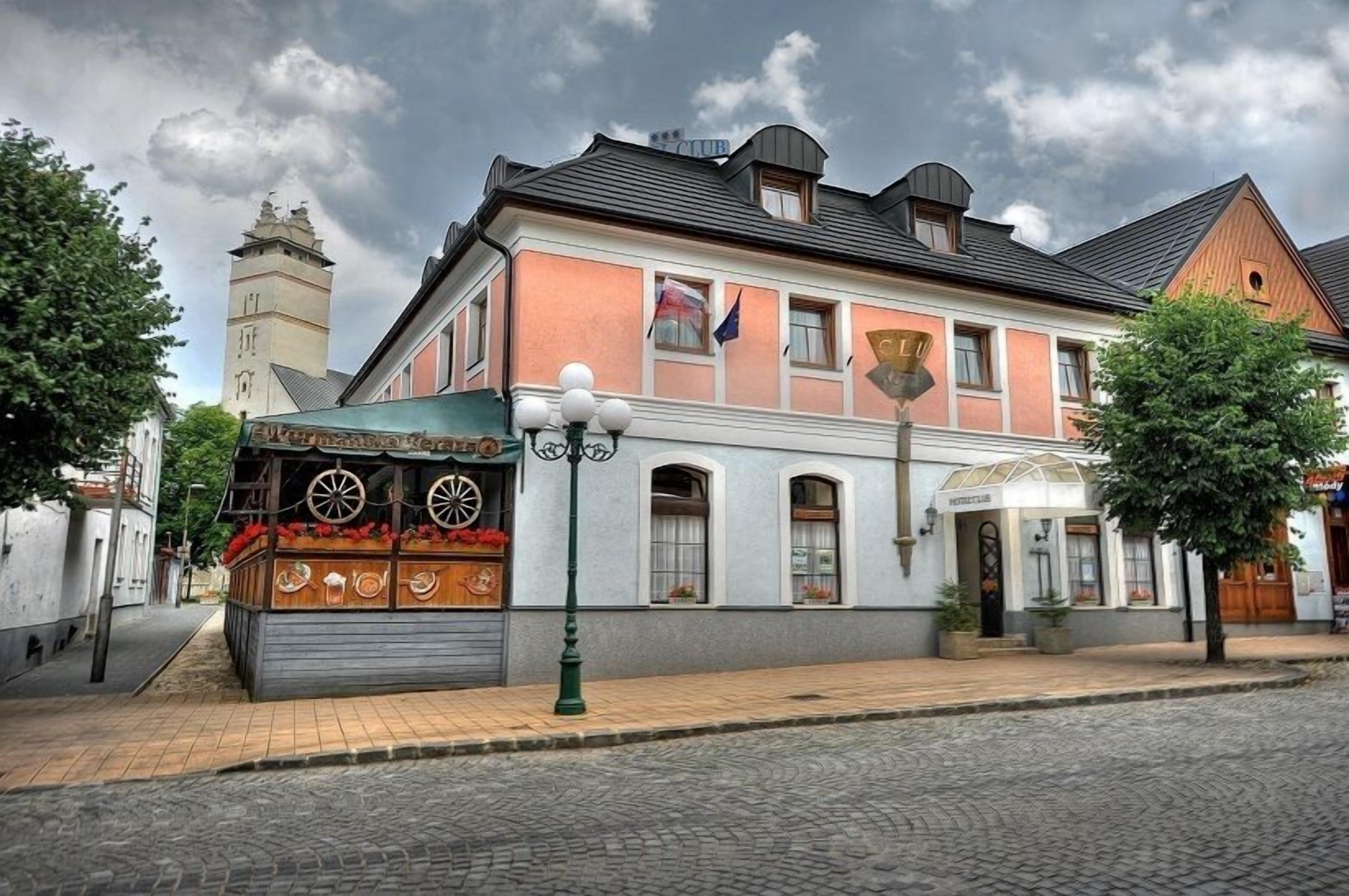 Um edifício tradicional com uma placa de restaurante, um relógio e uma torre ao fundo.