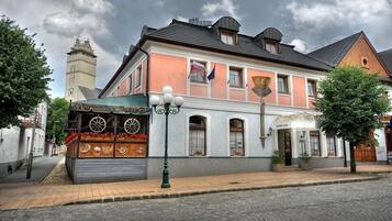 Um edifício tradicional com uma placa de restaurante, um relógio e uma torre ao fundo.