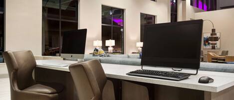 Um espaço de escritório moderno com uma mesa, duas cadeiras, um computador e uma janela grande.