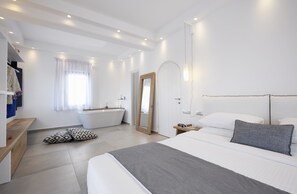 Quarto de hotel moderno com uma cama grande, uma banheira e uma toucador com espelho.