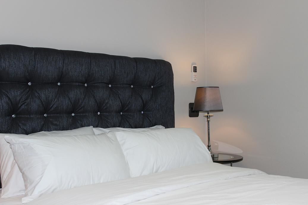 Cama bem arrumada com lençóis brancos e cabeceira estofada.