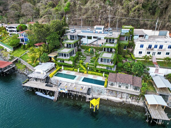 Um imóvel costeiro com vários edifícios, piscina e um cais que se projeta para a água.