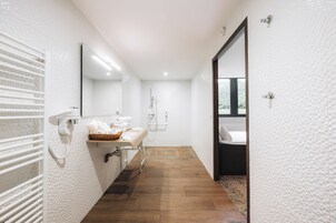 Casa de banho moderna com chuveiro, pia e espelho.