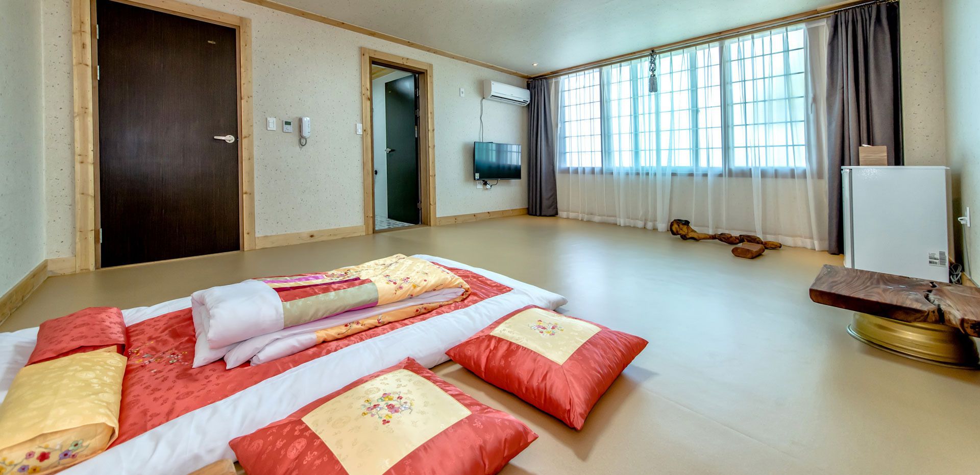 Quarto de hotel com cama grande, televisão, ar condicionado e janela com cortinas.