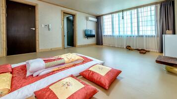 Quarto de hotel com cama grande, televisão, ar condicionado e janela com cortinas.