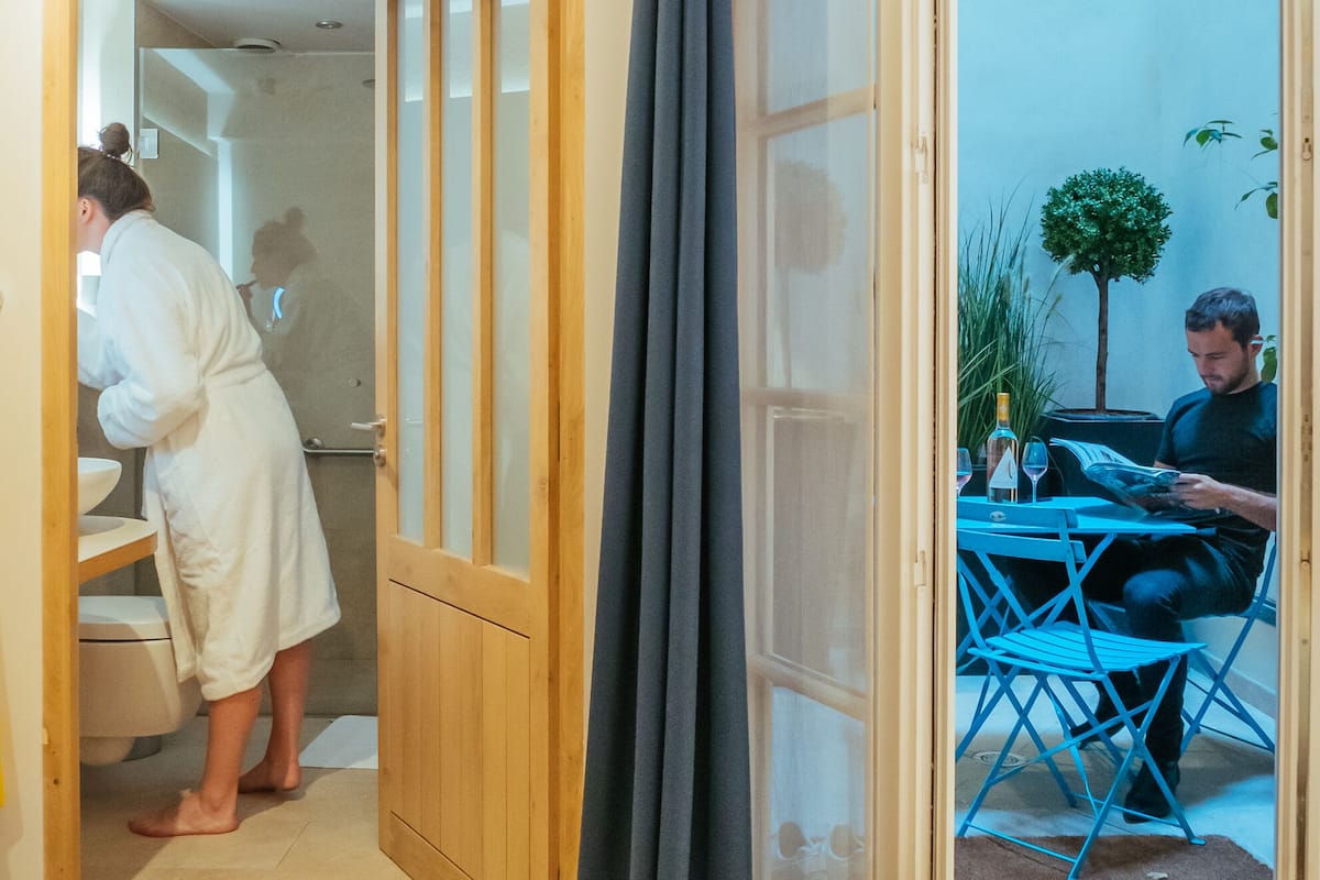 Quarto com cama, banheiro com pia e área de refeições com mesa e cadeiras.