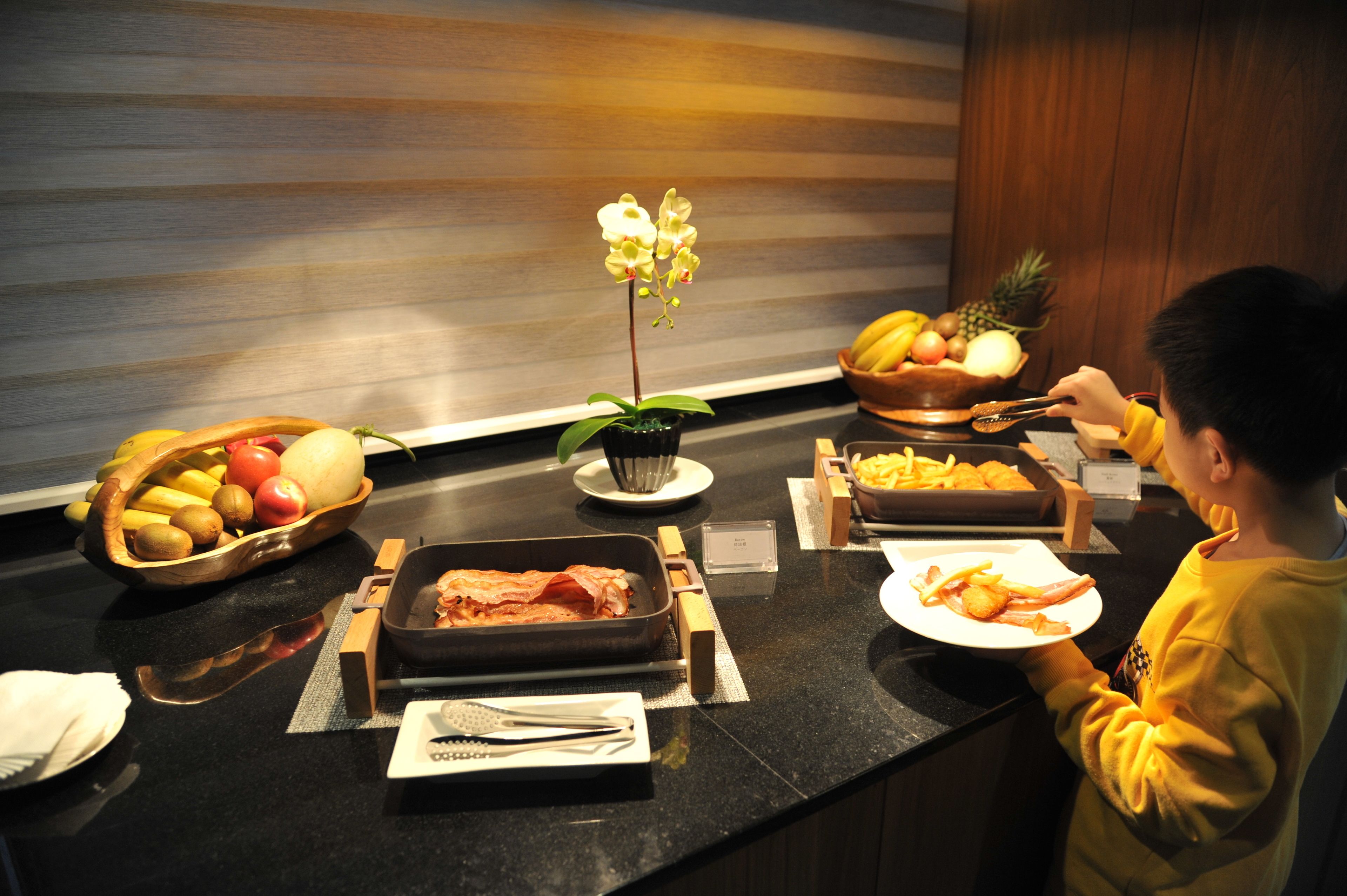Disposição de buffet com diversas frutas, legumes e uma orquídea central.