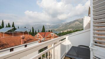 Varanda com vista para uma montanha, um edifício com telhado vermelho e painéis solares.