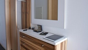 Um banheiro moderno com toucador de madeira, um espelho e um tablet no balcão.