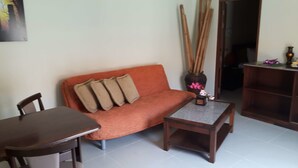 Uma sala de estar com sofá, mesa de centro, mesa de jantar e um armário.