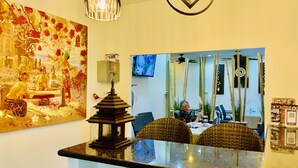 Uma sala de jantar com um quadro grande, um candeeiro tradicional e uma televisão ao fundo.
