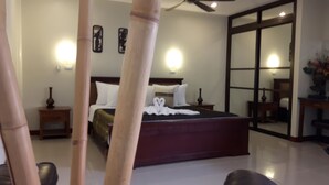 Quarto de hotel com uma cama grande, mesas de cabeceira, luzes fixadas na parede e uma porta de vidro deslizante.