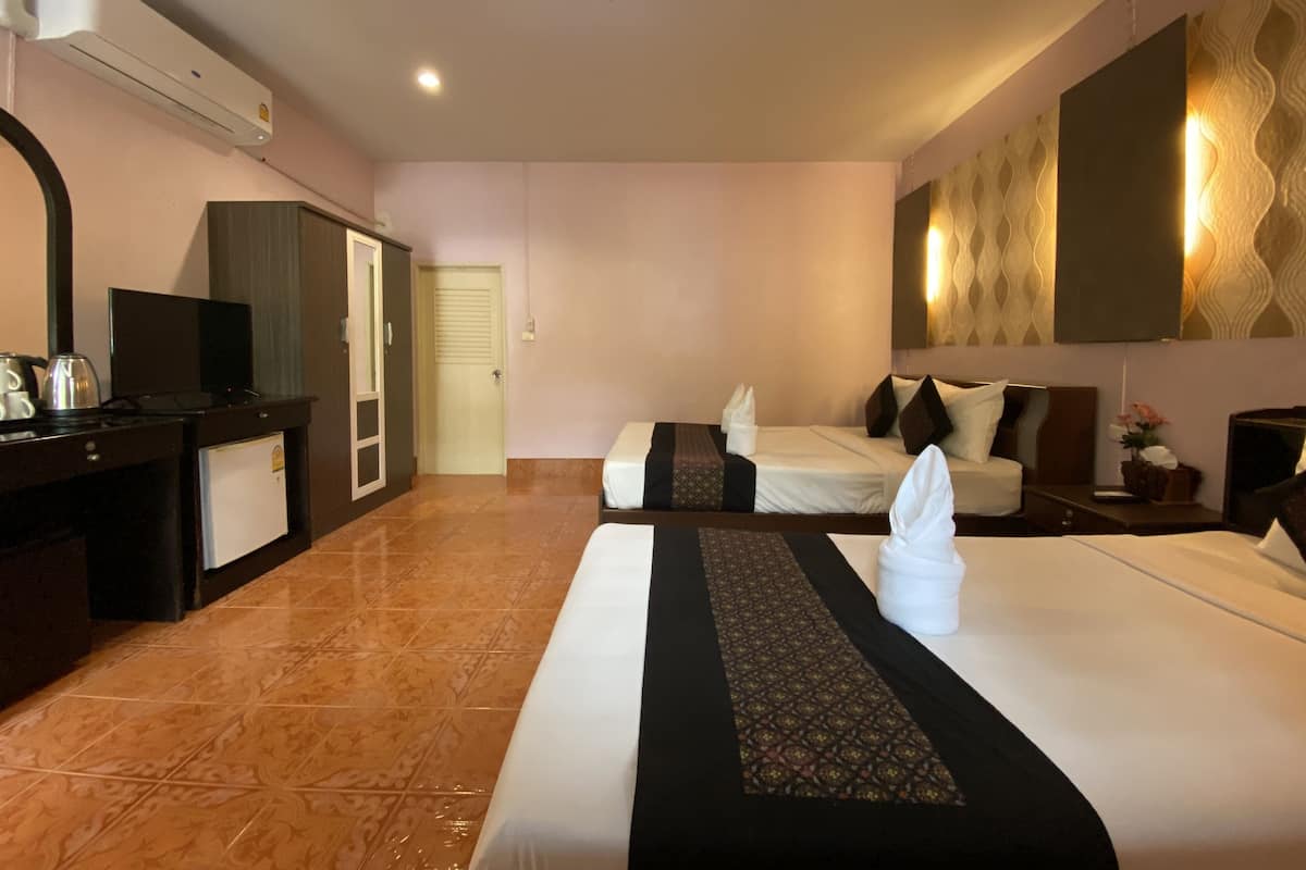 Quarto de hotel com duas camas, uma mesa de escritório com computador, guarda-roupa e porta de banheiro.
