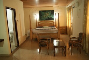 Quarto com cama de dossel, mesa de cabeceira de madeira, uma cadeira, uma mesa e um espelho.