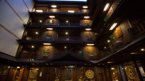 Um edifício de vários andares com estilo arquitetônico tradicional, apresentando varandas, guarda-corpos de madeira e uma entrada central com degraus.