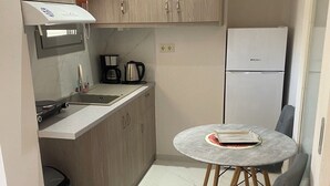 Uma cafeteira/bule, um frigorífico, uma placa de cozinha