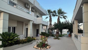 Um edifício moderno com um pátio central, palmeiras e um jardim bem cuidado.