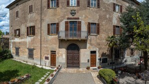 Um edifício histórico com entrada central, várias janelas com persianas e uma varanda.