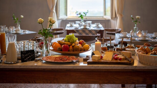 Um buffet de café da manhã com frutas, queijos e pães de diversas opções.