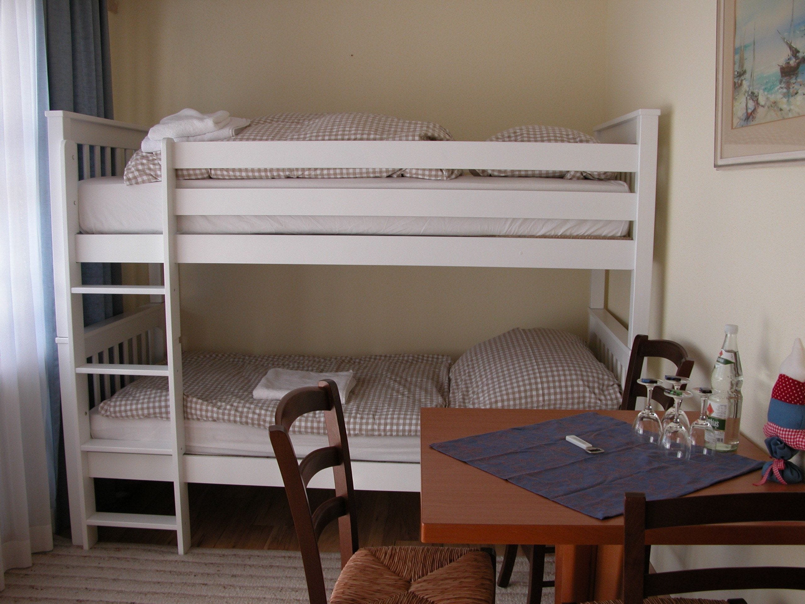 Uma cama beliche com uma mesa e cadeiras num quarto.