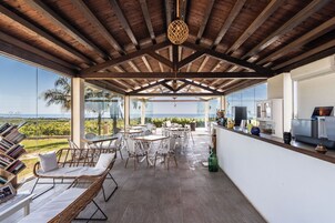 Uma área externa coberta com assentos, cozinha e vista para a paisagem.