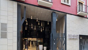 A entrada do Hotel Catalonia Magdalenen, com design moderno, apresenta grandes vasos de plantas e luminárias pendentes.