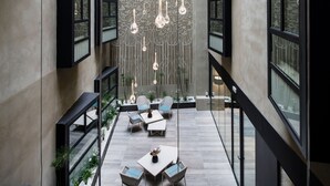 Um interior moderno com área de estar central, luminárias pendentes e grandes janelas.