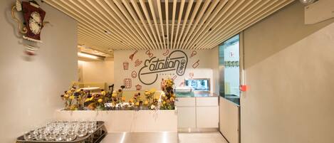 Um interior moderno com área de cozinha, um balcão com copos e uma parede com um logotipo.