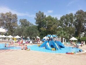Uma piscina com escorregador e espreguiçadeiras.