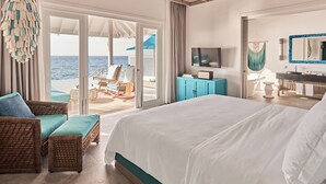 Um quarto espaçoso com uma cama grande, televisão, banheiro com pia e espelho, e varanda com vista para o mar.