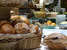 Diversos pães e doces dispostos em cestas e sobre uma mesa.