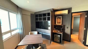 Uma sala de estar moderna com área de refeições, cozinha planejada e uma janela ampla.