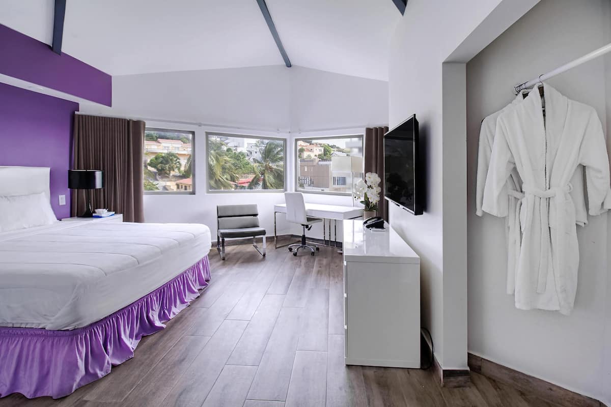 Quarto de hotel moderno com cama, escrivaninha e televisão.