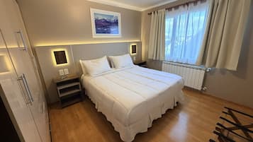 Quarto de hotel com uma cama grande, mesas de cabeceira, vista para o exterior e um quadro pendurado na parede.