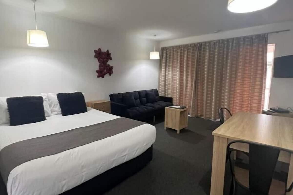 Quarto de hotel com cama, sofá, escrivaninha e cadeira.