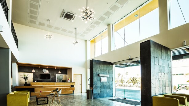 Um hall amplo com balcão de recepção, área de estar e uma grande janela que proporciona iluminação natural.