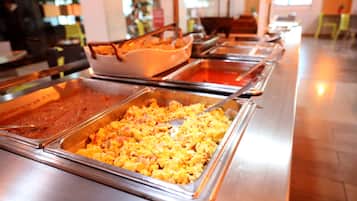 Buffet com diversas opções de comida, incluindo ovos mexidos e outros pratos.
