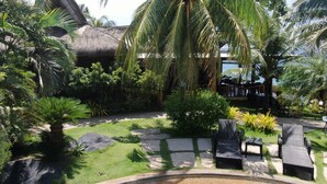 Um resort tropical com palmeiras, uma construção de palha e área de estar ao ar livre.