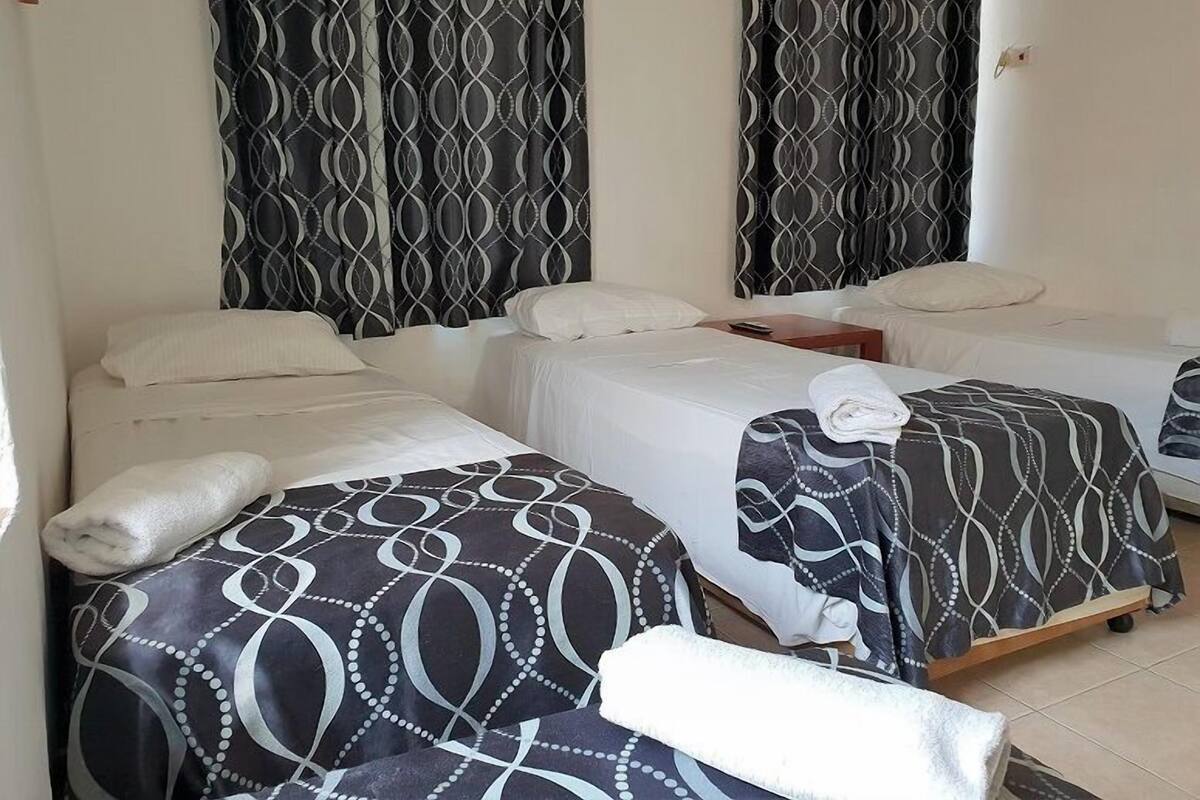 Quarto de hotel com duas camas, cada uma com uma colcha estampada e almofadas brancas.